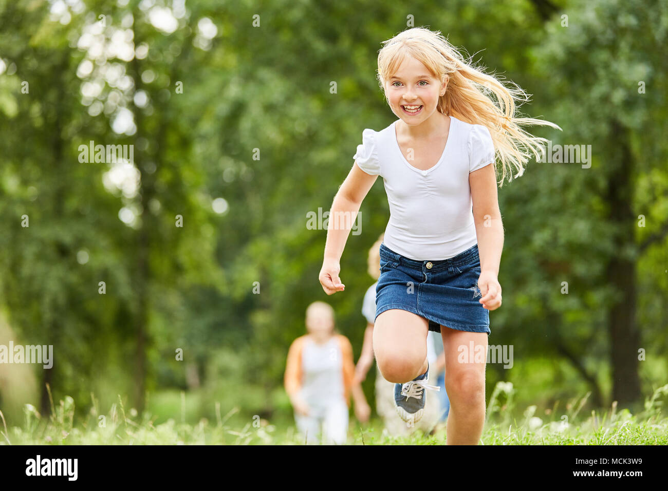 Blonde girl makes a race over a meadow and has fun Stock Photo - Alamy