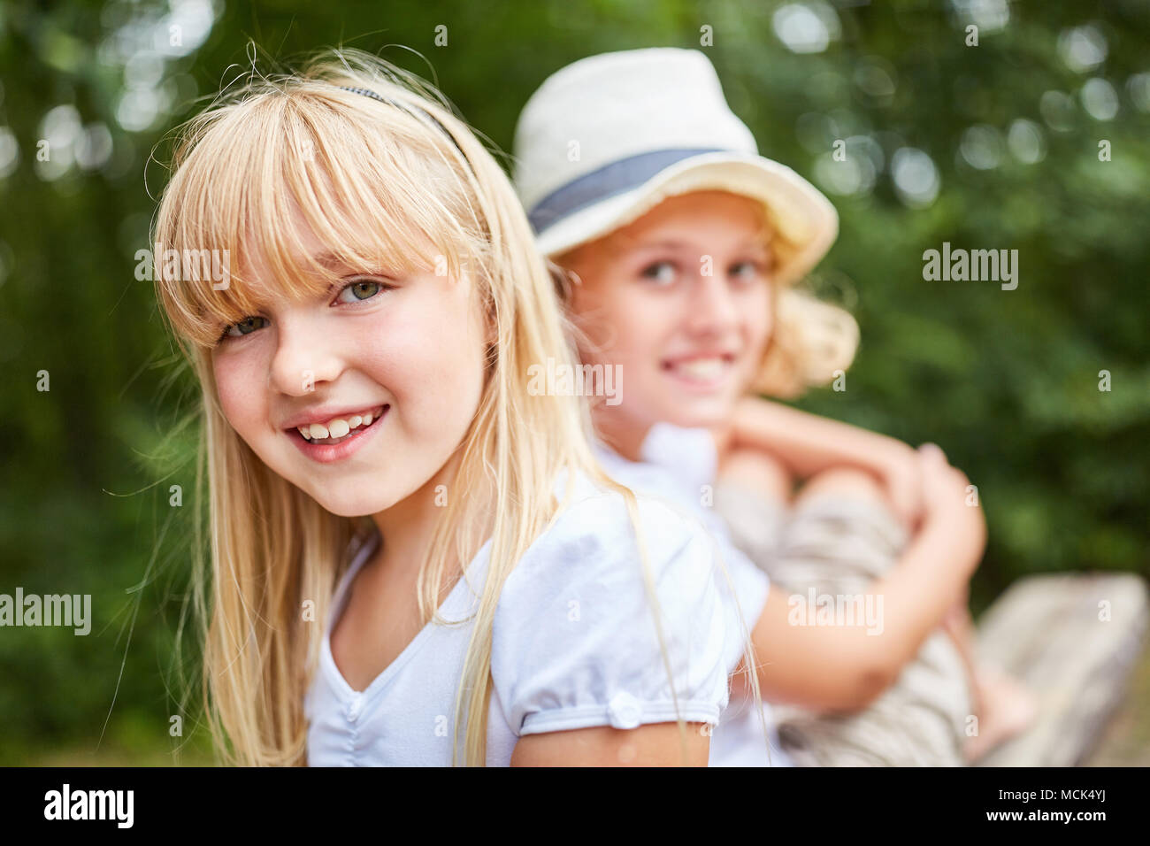 Blond girl happily smiles with her brother in the background Stock ...