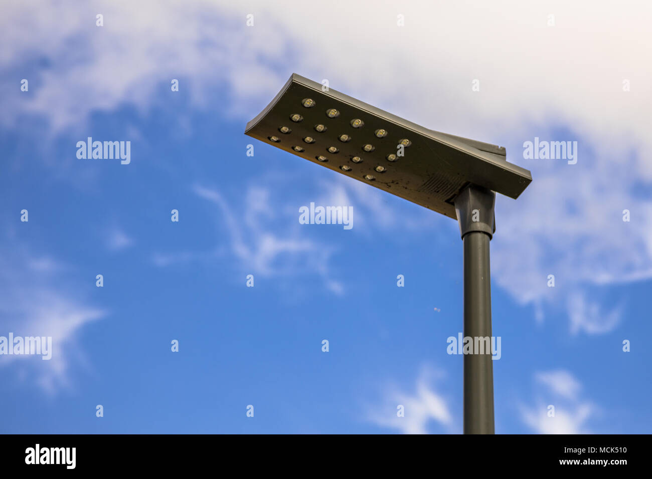 LED street light with black pole and armature aigainst blue summer sky ...