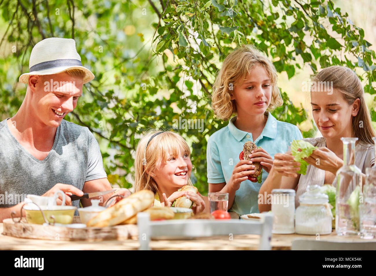 Family and children having breakfast or brunch in the garden in summer ...