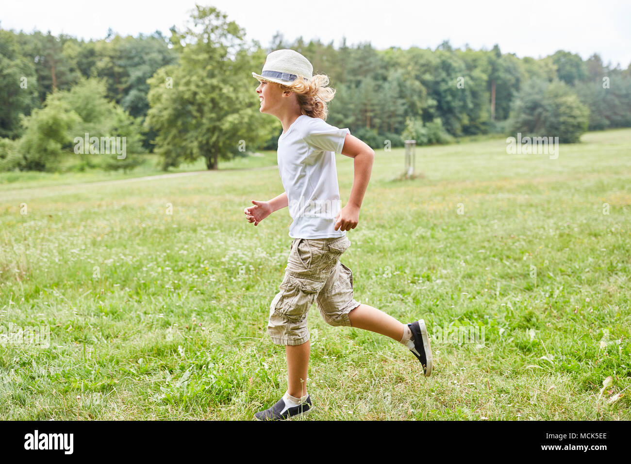 Blond boy happily runs across a meadow in summer on vacation Stock ...