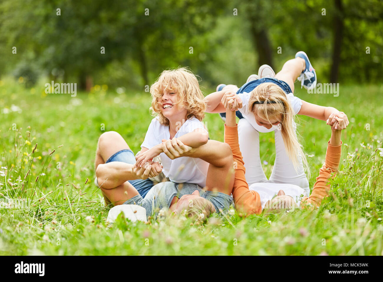 Children are romping with their parents in the grass around in the ...