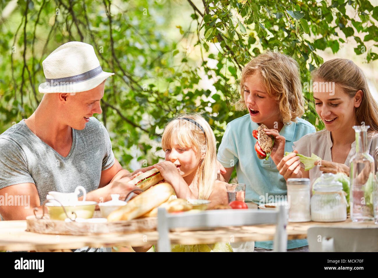 Family and kids together having breakfast in the summer in the garden ...