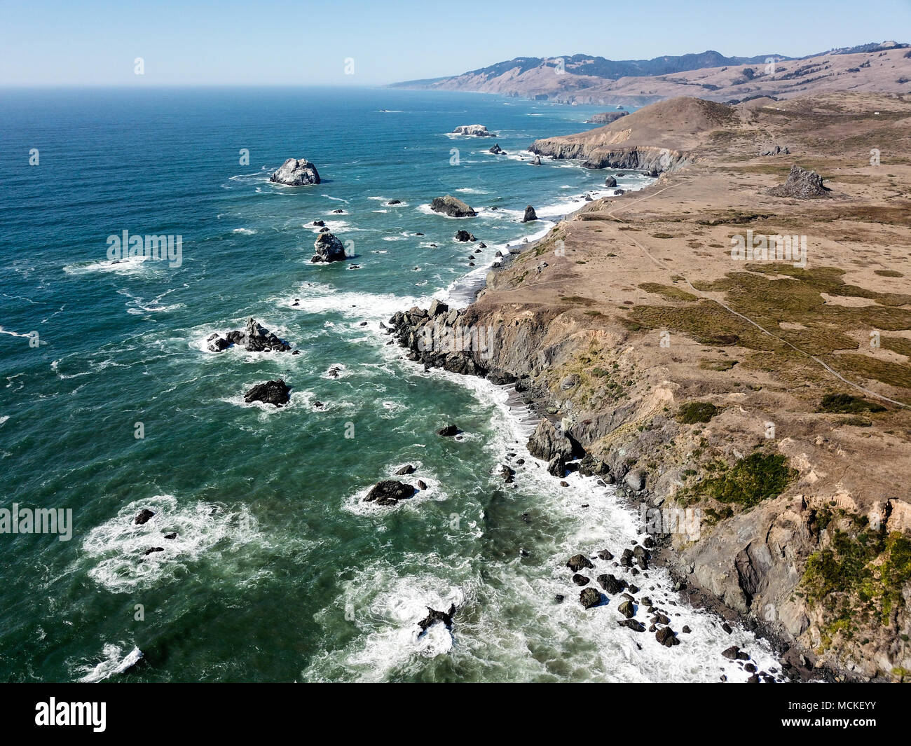 The cold waters of the Pacific Ocean wash against the scenic and rugged ...