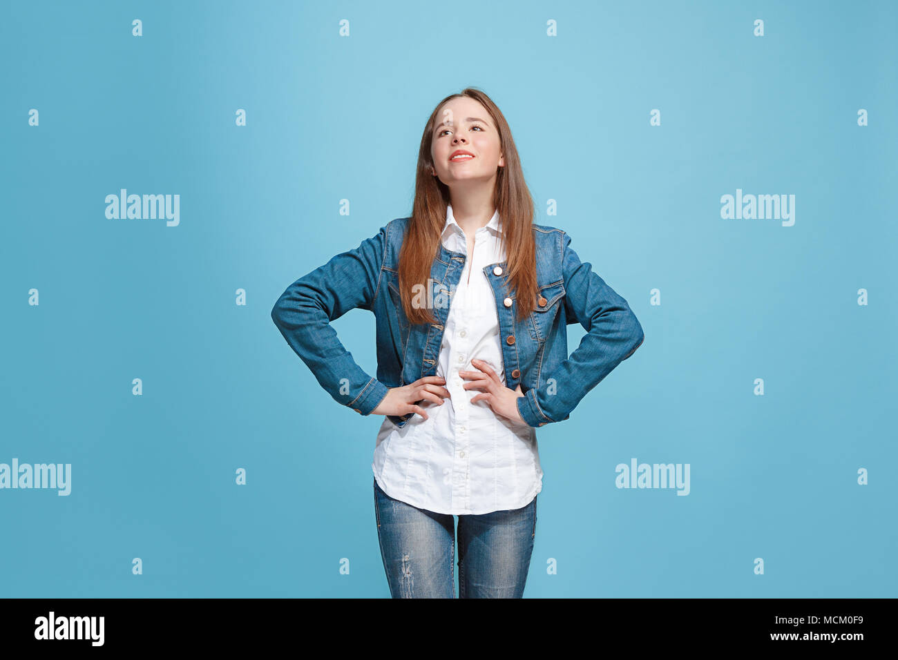 The happy teen girl standing and smiling against blue background Stock ...