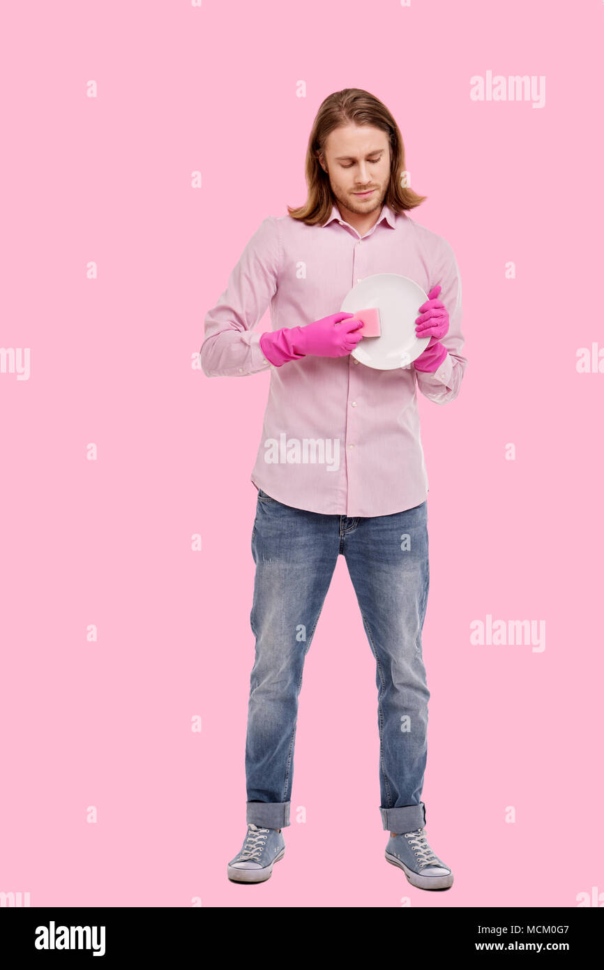 Pleasant young man cleaning plate thoroughly Stock Photo - Alamy