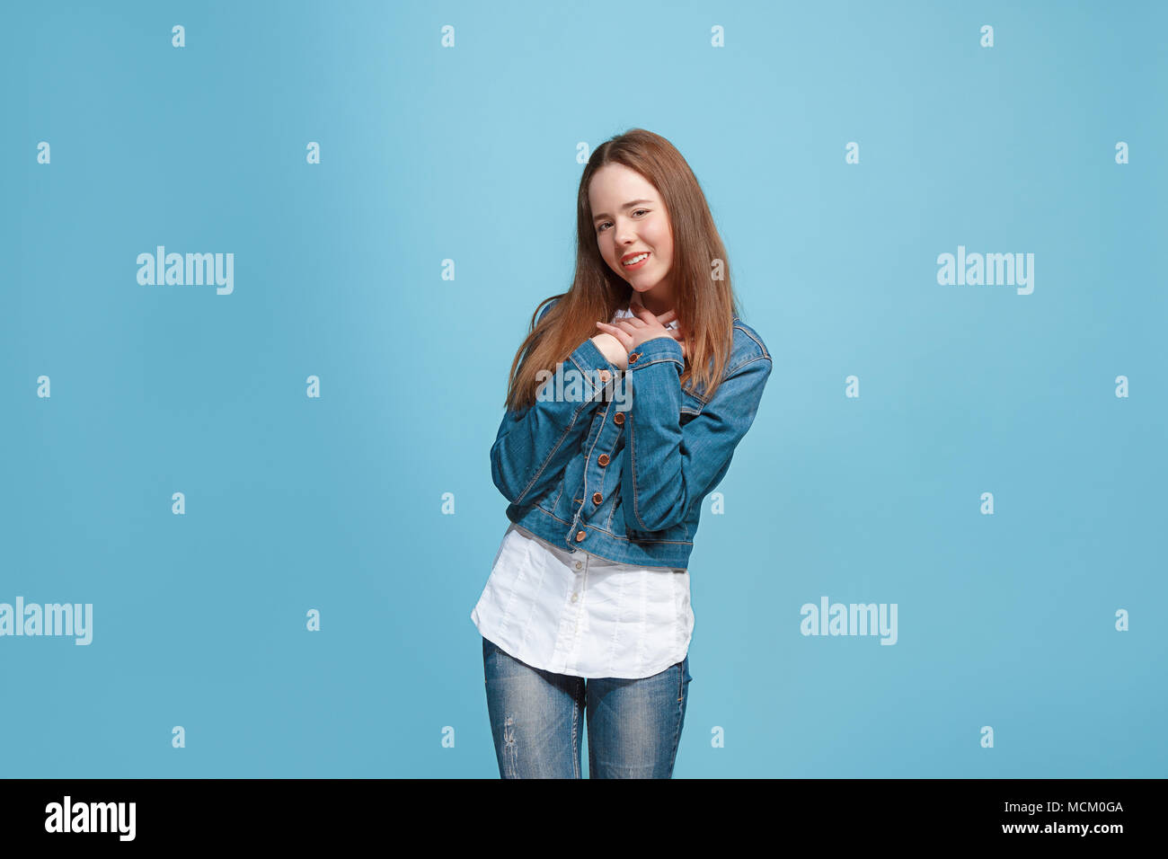 The happy teen girl standing and smiling against blue background Stock ...