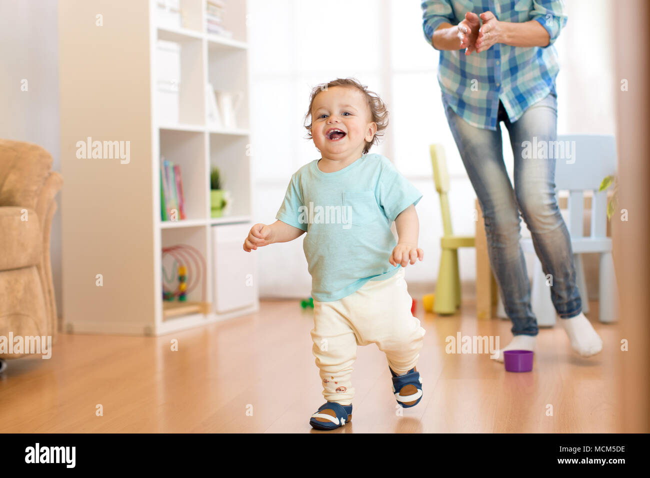 Baby boy running in the living room with his mother Stock Photo - Alamy