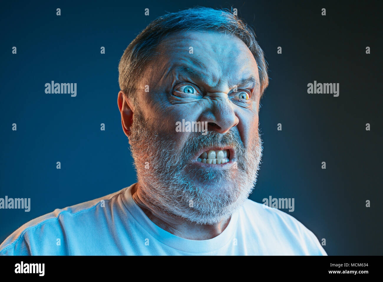 The senior emotional angry man screaming on blue studio background ...