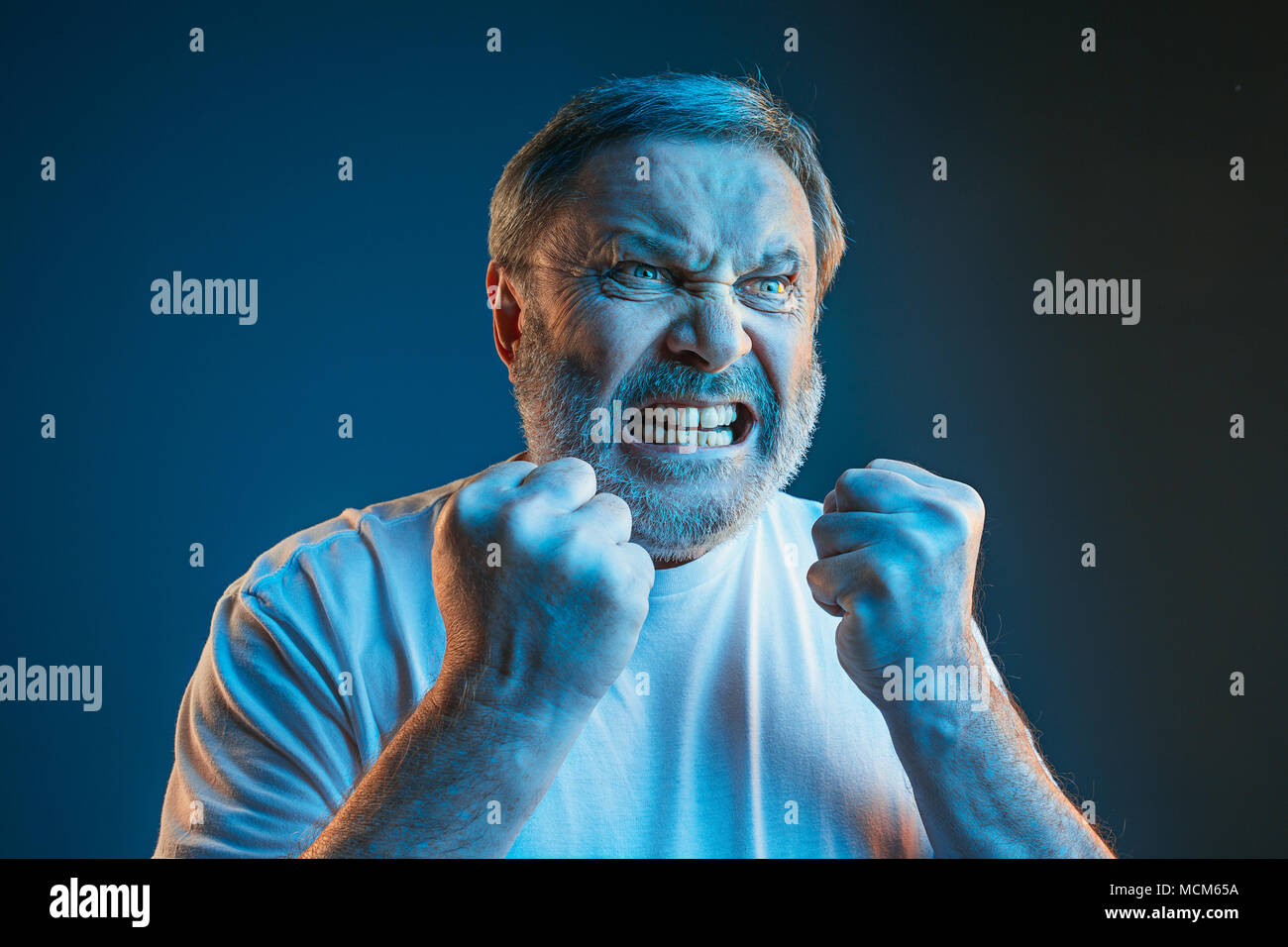 The senior emotional angry man screaming on blue studio background ...