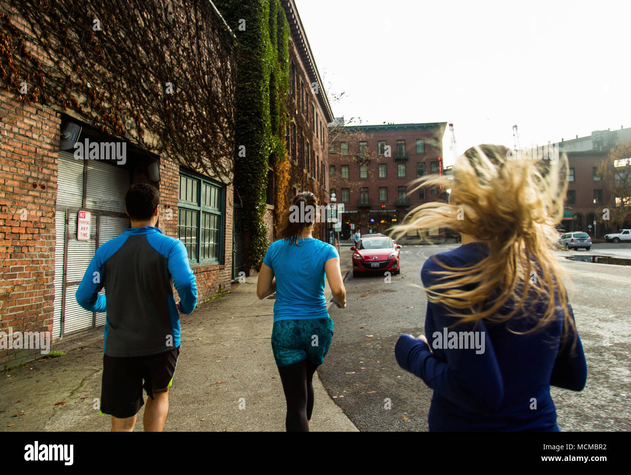 Rear view of male and female runners jogging in street, Pioneer Square ...