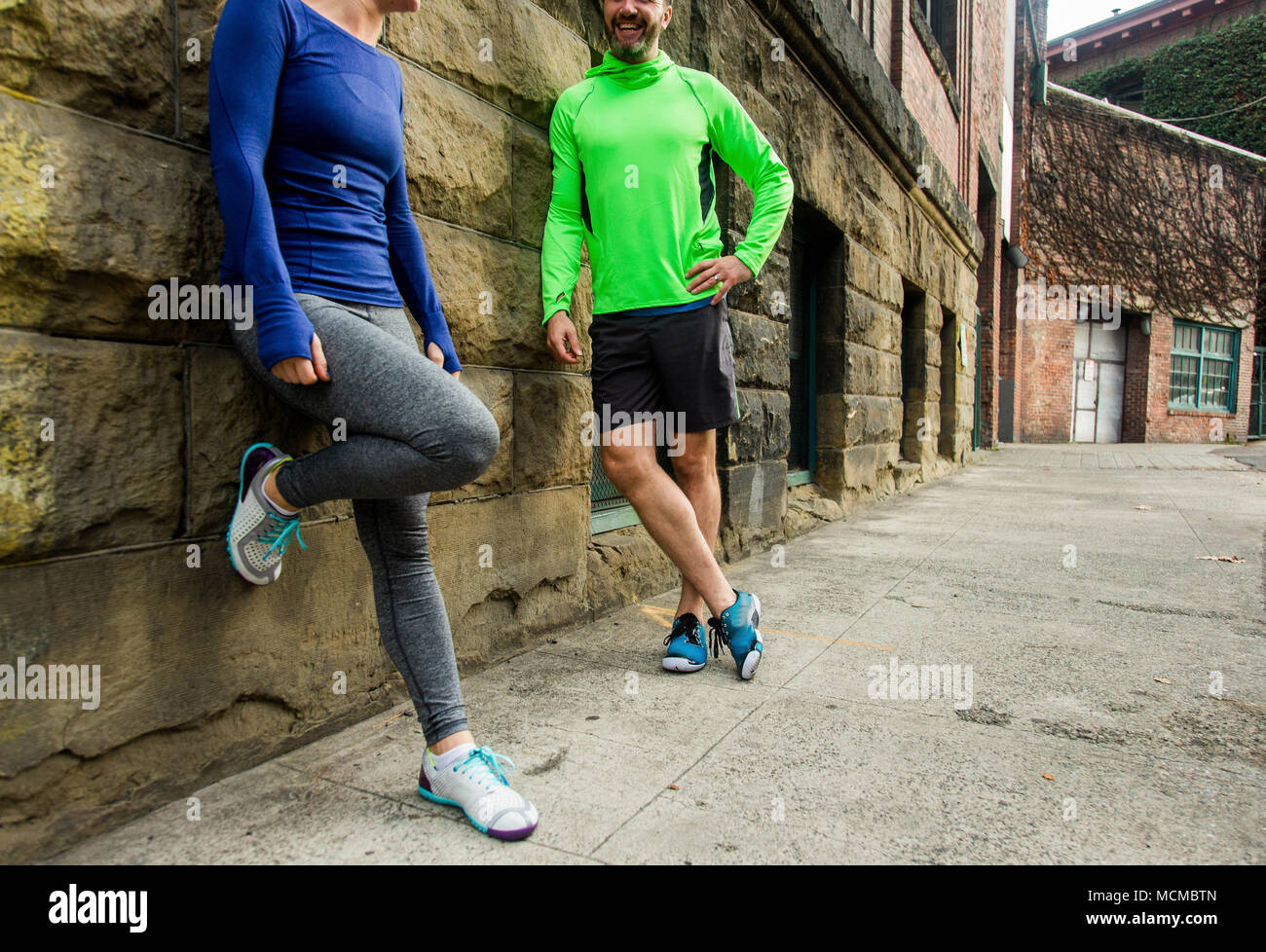 Male and female runners talking while resting during jogging hi-res ...