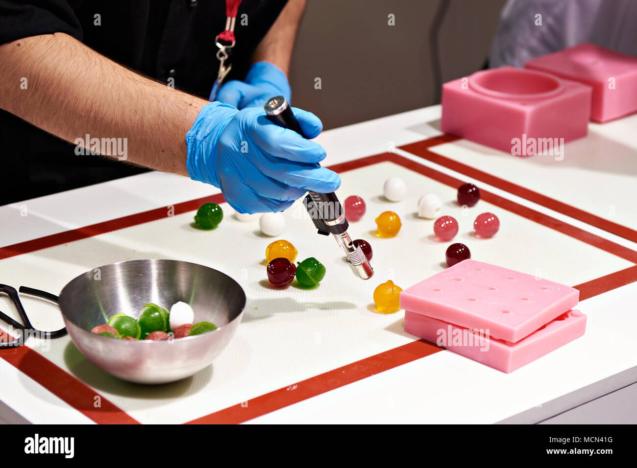 Confectioner with a burner prepares color sweet candy balls Stock Photo ...