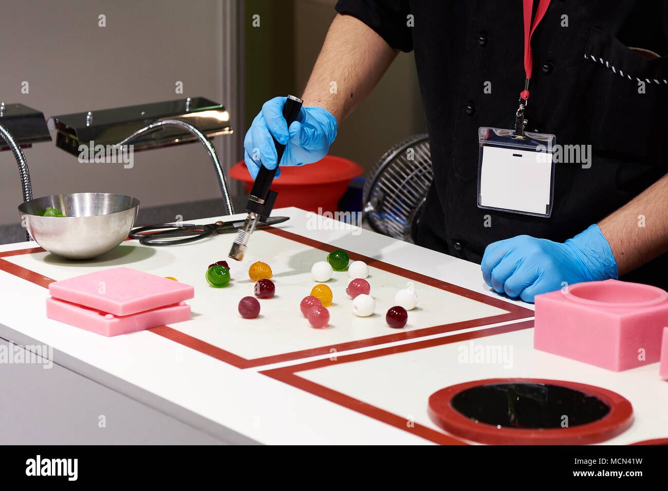 Confectioner with a burner prepares color sweet candy balls Stock Photo ...
