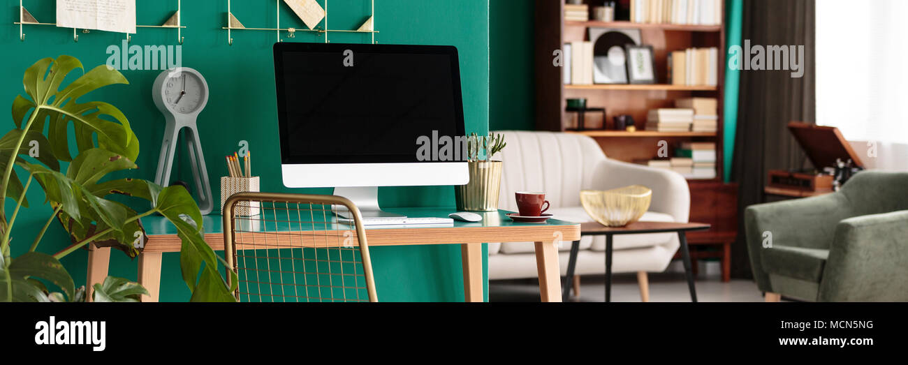Home office desk with a desktop computer by a teal green wall in a ...