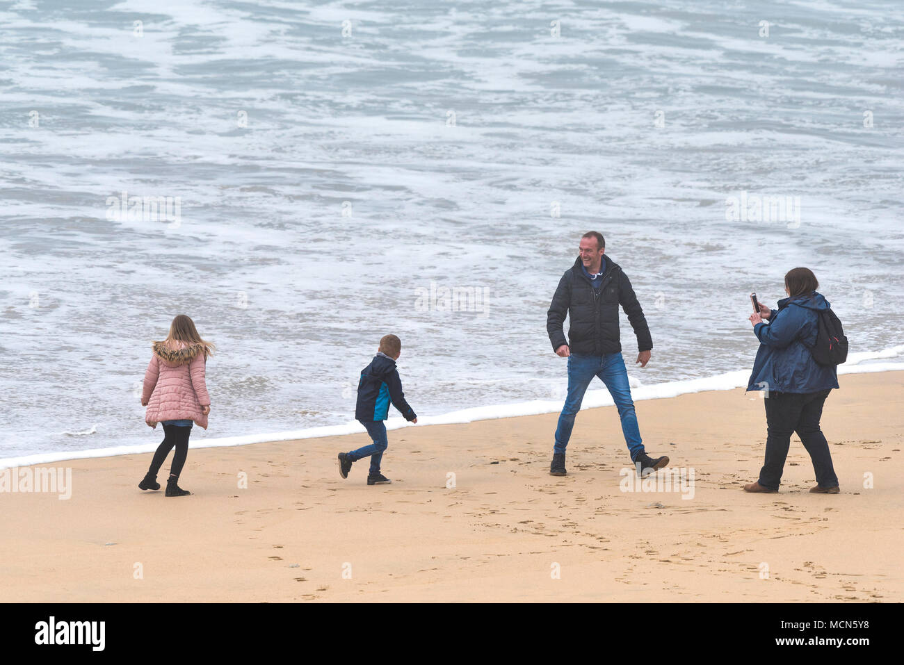A family having fun on a cold and windy Fistral Beach in Newquay ...