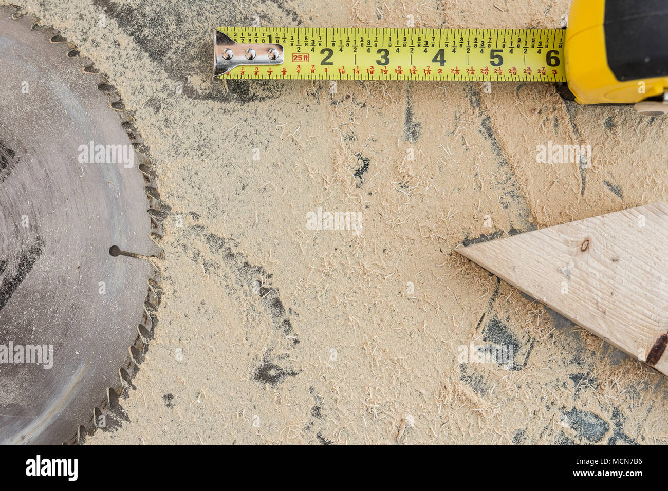 Overhead of shop table; sawdust, tape measure, wood block, saw blade ...