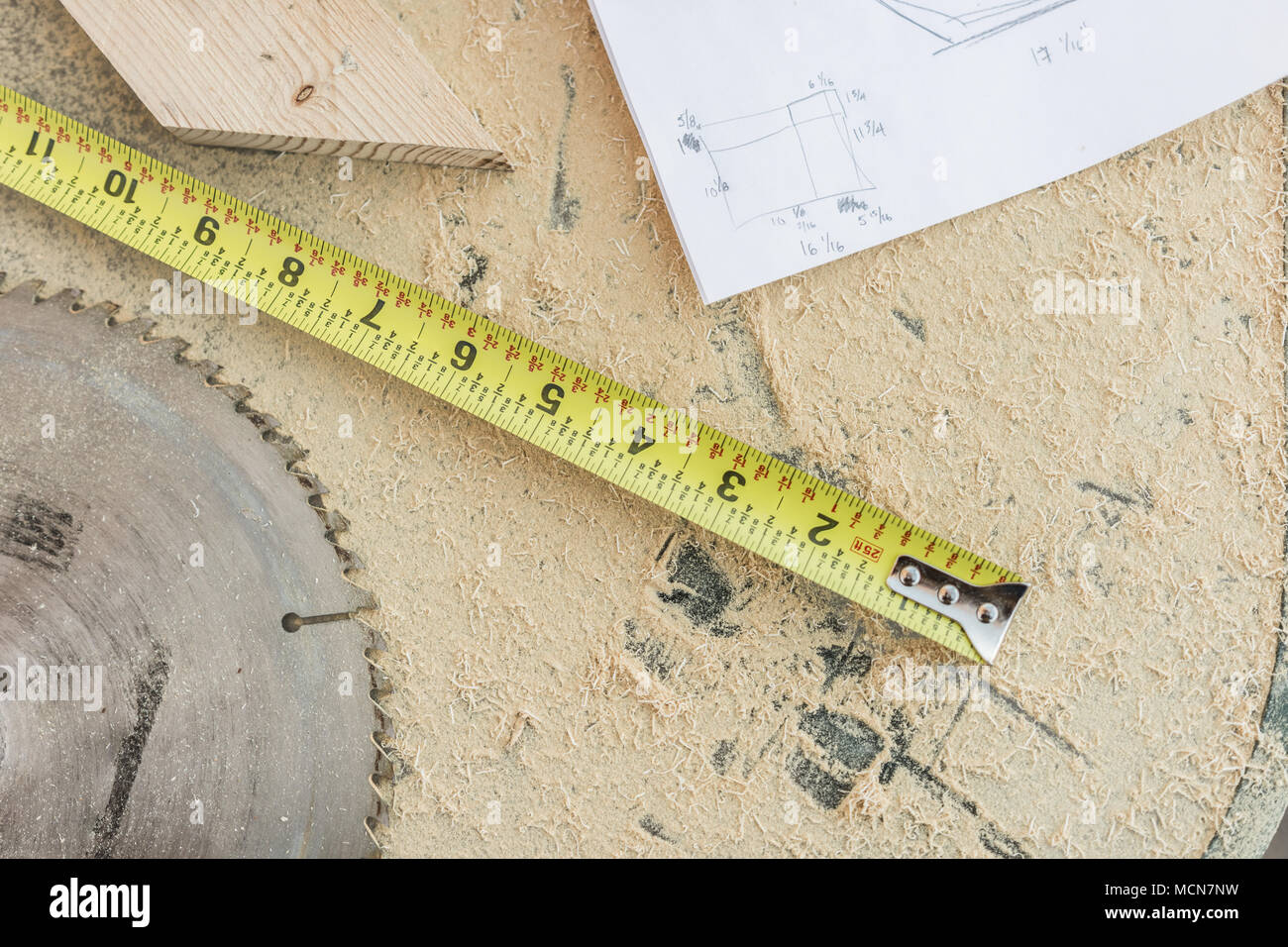 Overhead of shop table; sawdust, tape measure, wood block, saw blade ...