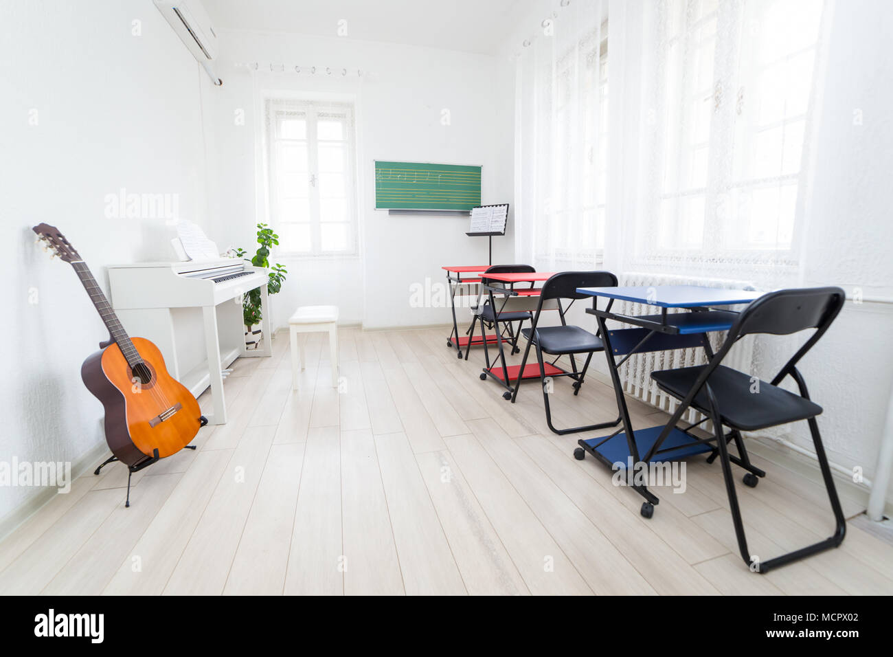 Modern daylight classroom for teaching music. Guitar, white piano and ...