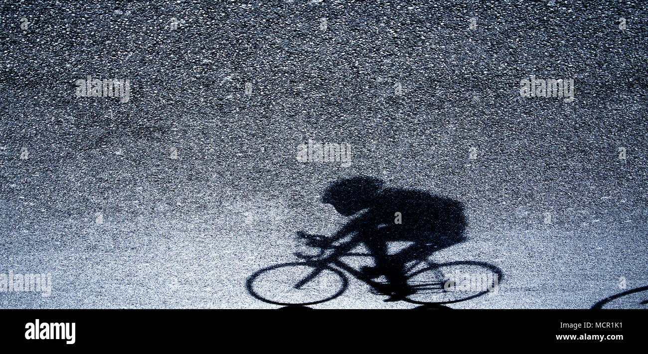 Blurry silhouette and shadow of a professional cyclist in black and ...