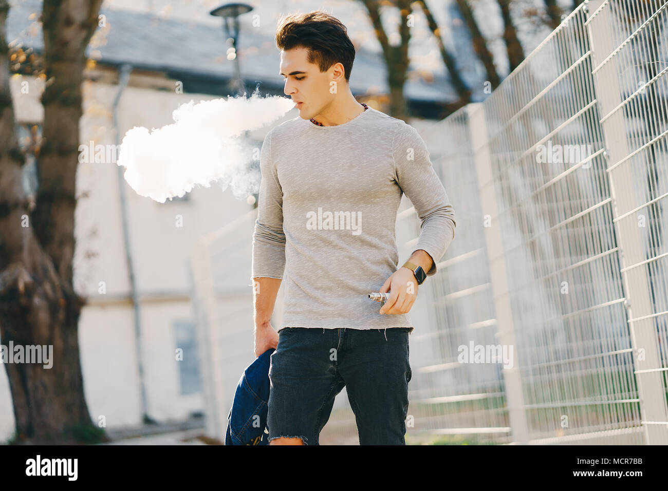 stylish man walking through the city smoking an e-cigarette Stock Photo ...