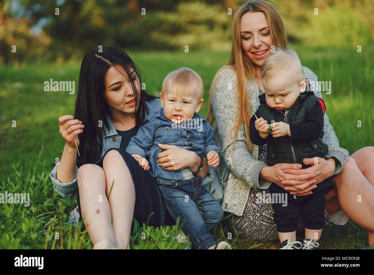 Two beautiful long-haired young women in the summer sunshine park are ...