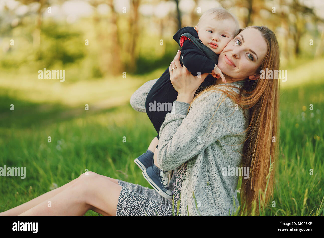 beautiful long-haired young mother in the summer sunshine park are ...