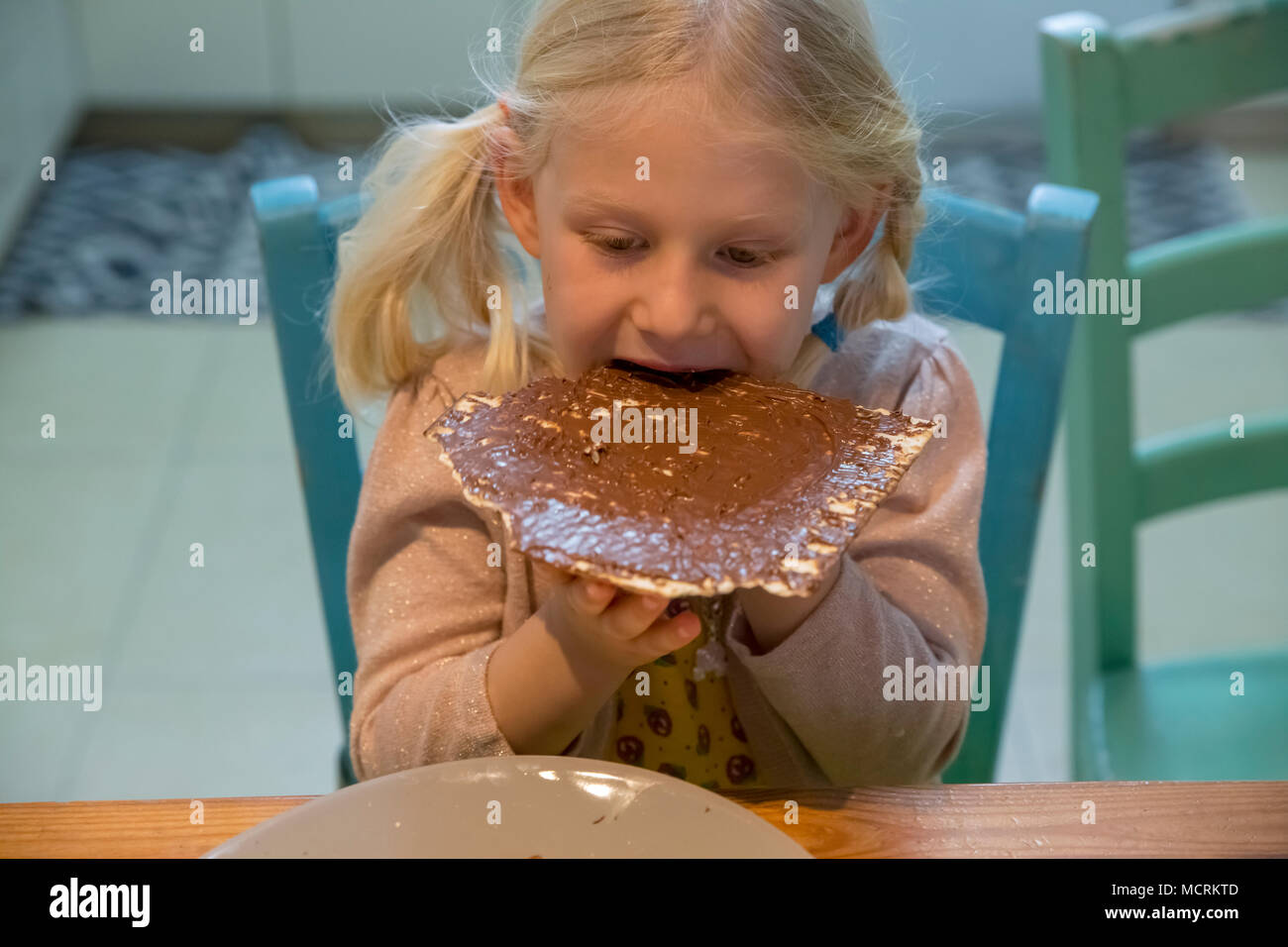 Portrait of a young girl of five eats Matzo with chocolate spread ...