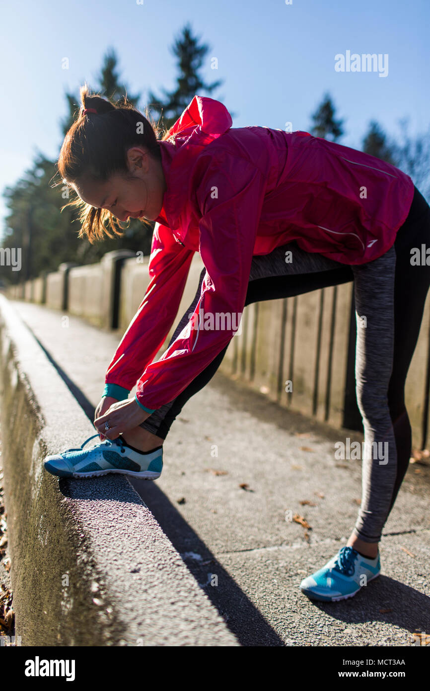 Female runner tying shoes on bridge hi-res stock photography and images ...