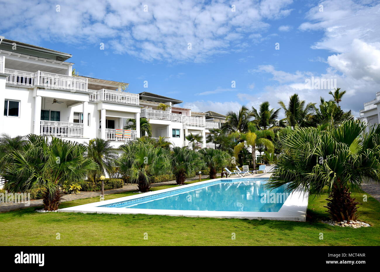 Beautiful white hotel building with the pool, blue skies and green ...