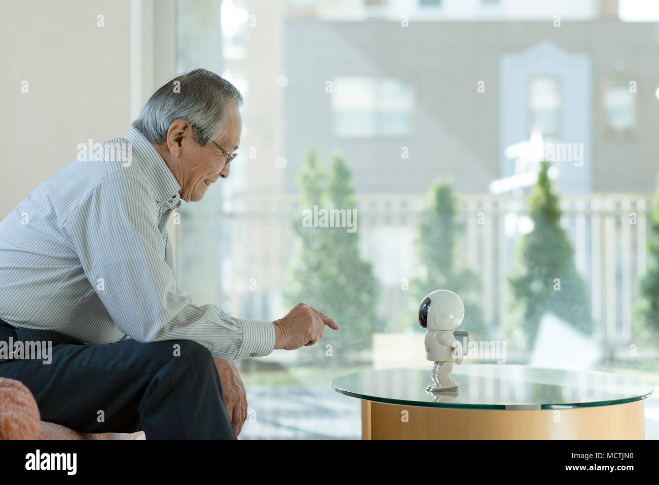 Senior man playing with robot Stock Photo - Alamy