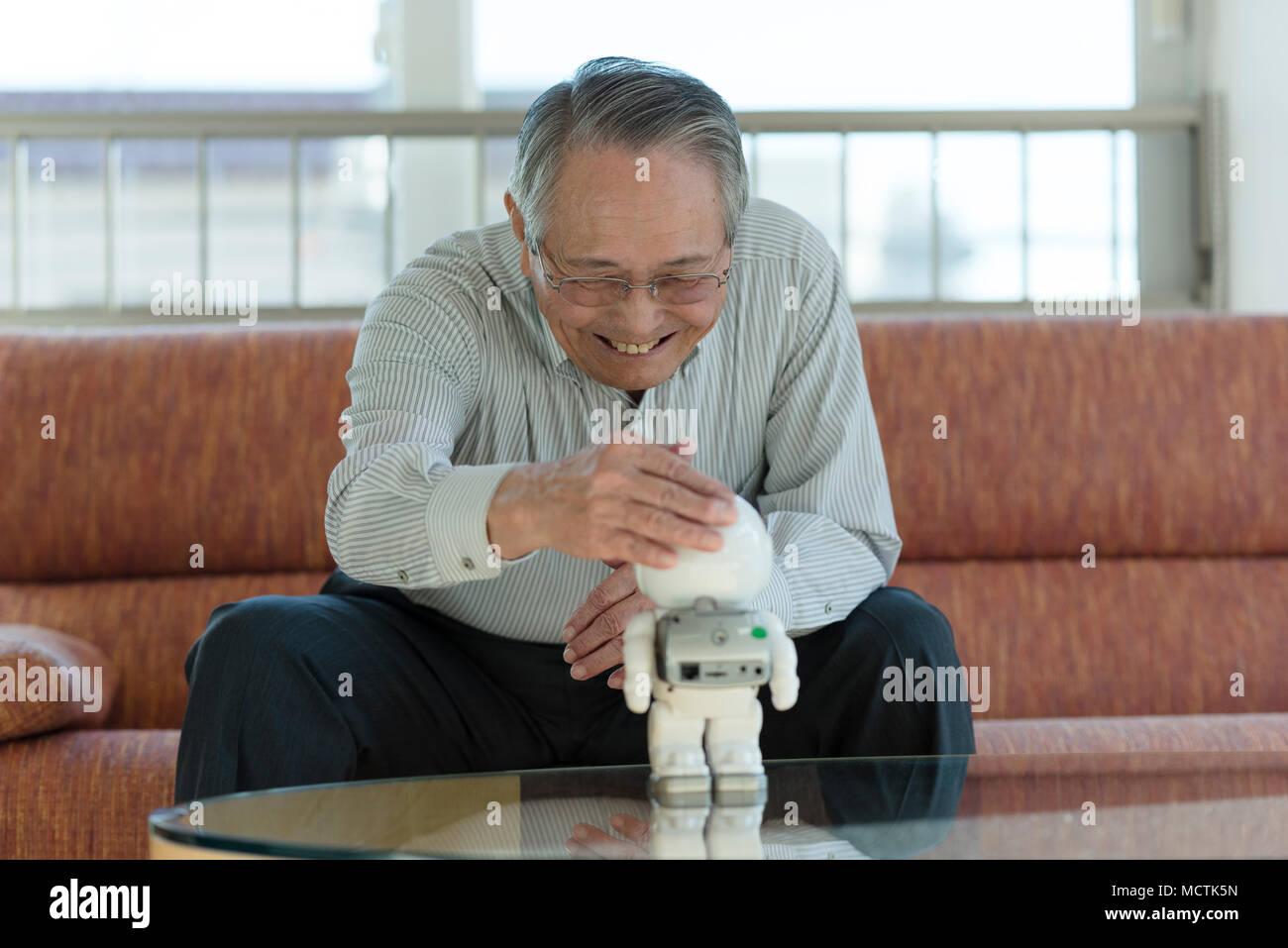 Senior man playing with robot Stock Photo - Alamy