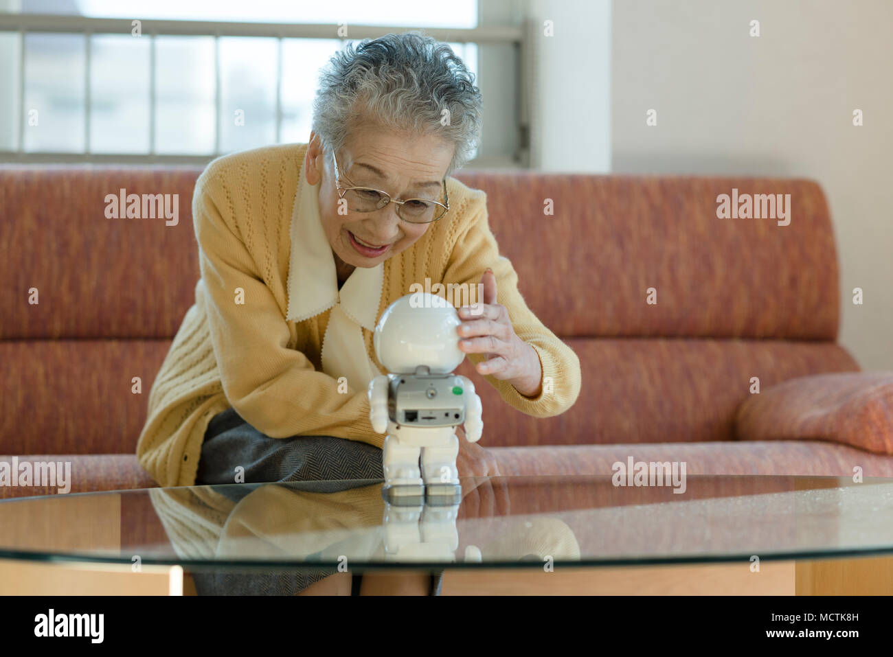 Senior woman playing with robot Stock Photo - Alamy