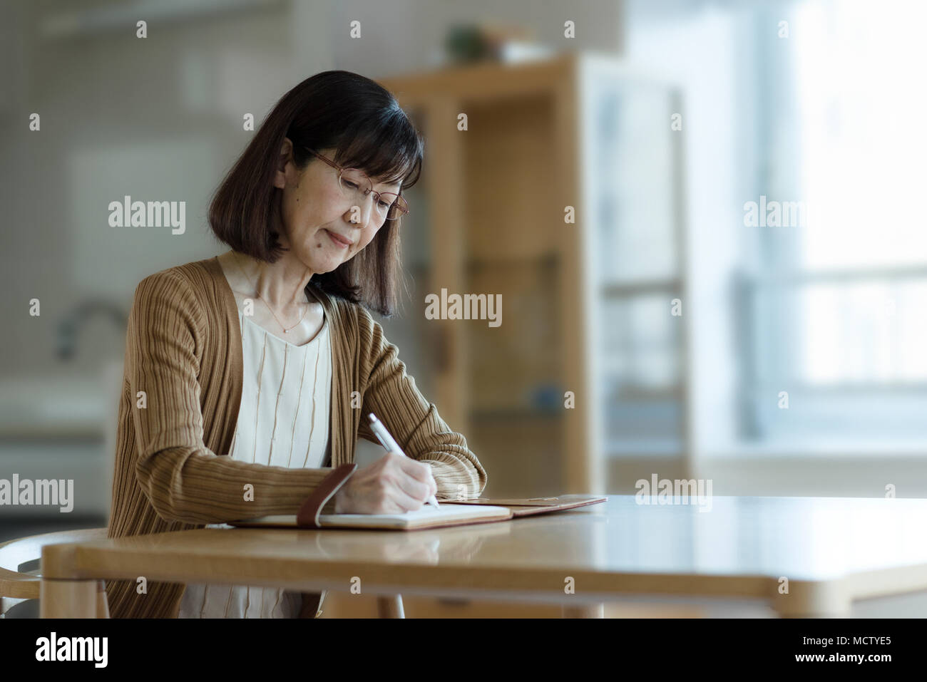 Senior woman writing ending notes Stock Photo - Alamy
