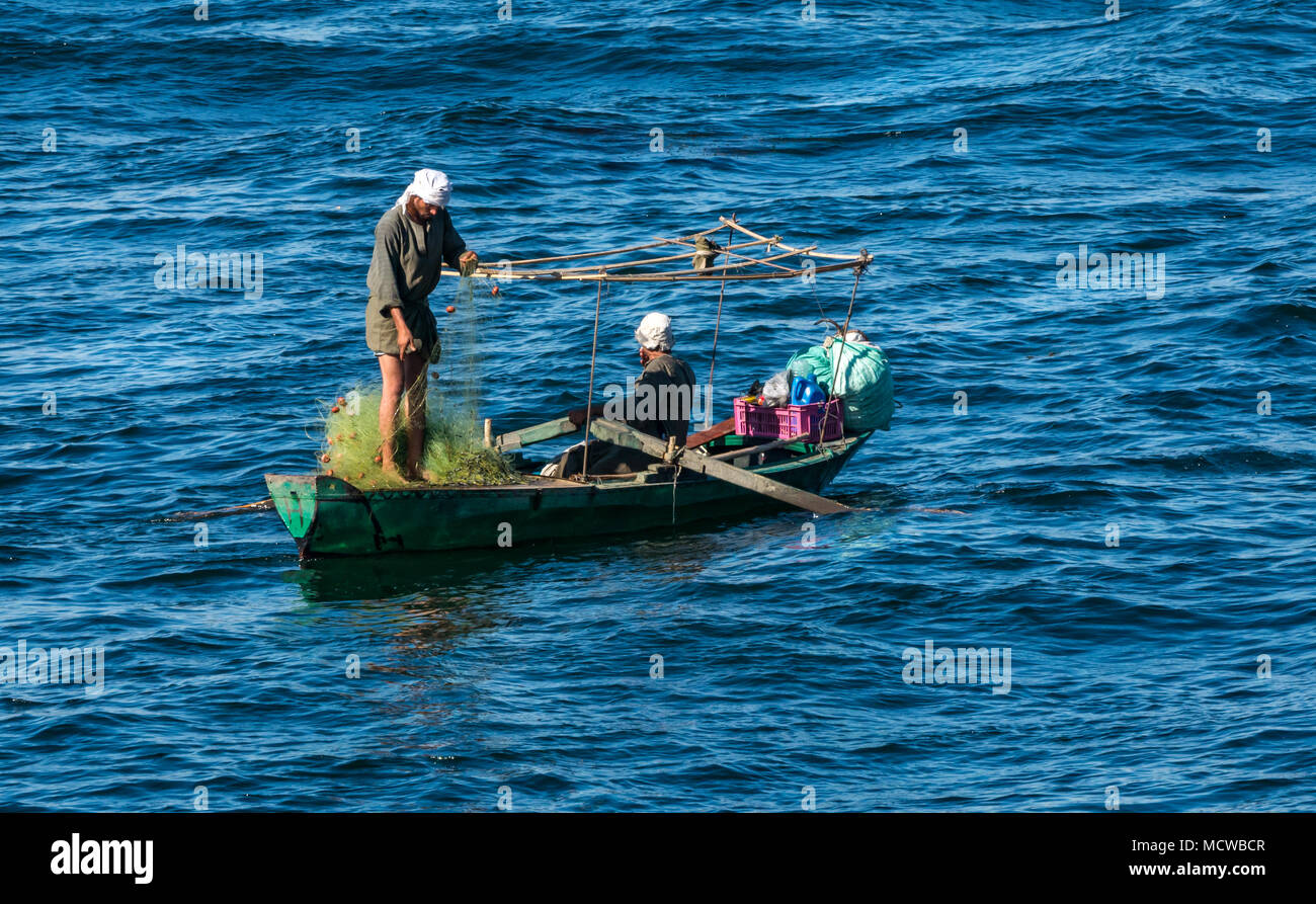 Two Egyptian local men in traditional dress and turbans in small rowing ...