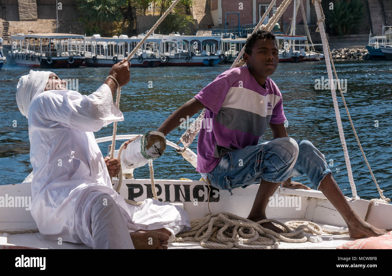 Old Egyptian man in white Jellabiya with grandson steering rudder of ...