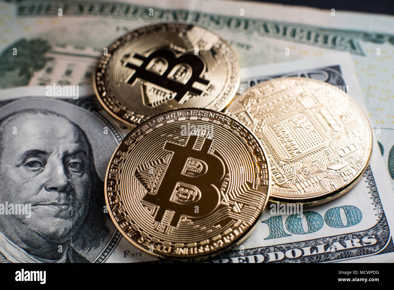 Bitcoin. Gold Bitcoins on a one hundred dollar bill close up Stock ...