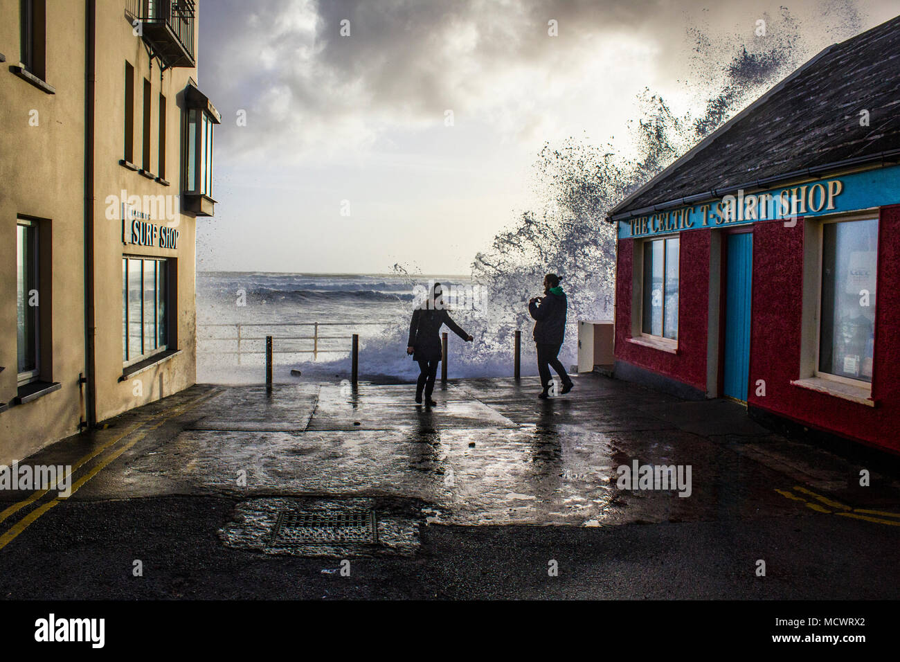 Couple Run from waves splashing up at high tide Stock Photo - Alamy