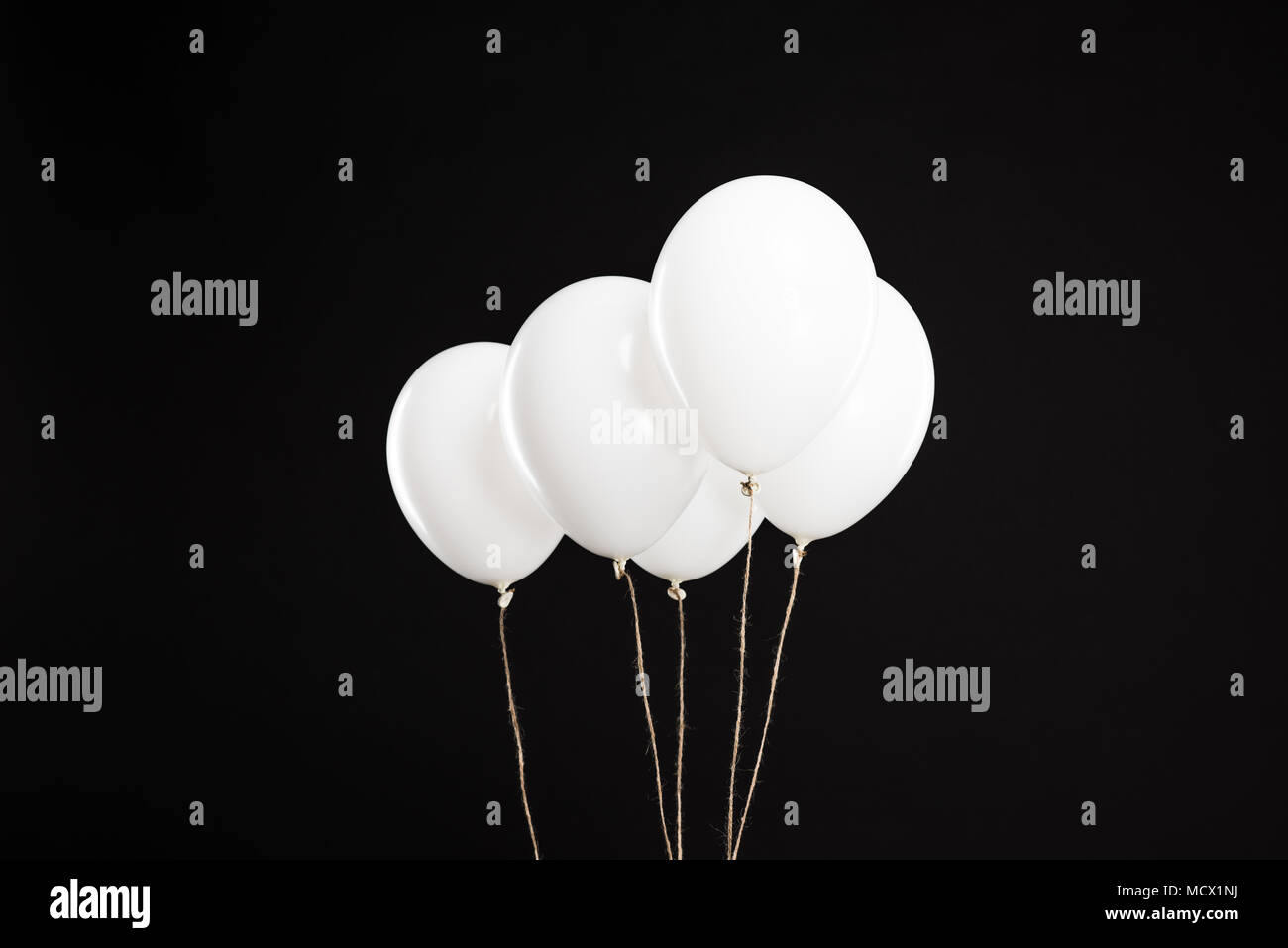 Bundle of white helium balloons isolated on black Stock Photo - Alamy
