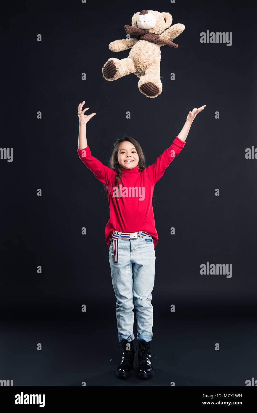 Happy kid throwing up teddy bear isolated on black Stock Photo - Alamy