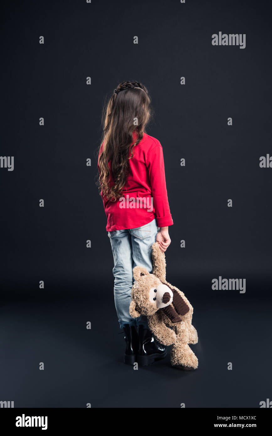 Rear view of kid holding teddy bear isolated on black Stock Photo - Alamy