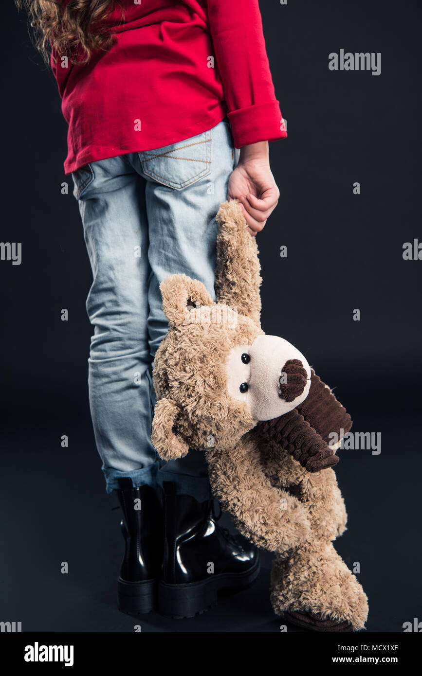 Cropped image of kid holding teddy bear isolated on black Stock Photo ...