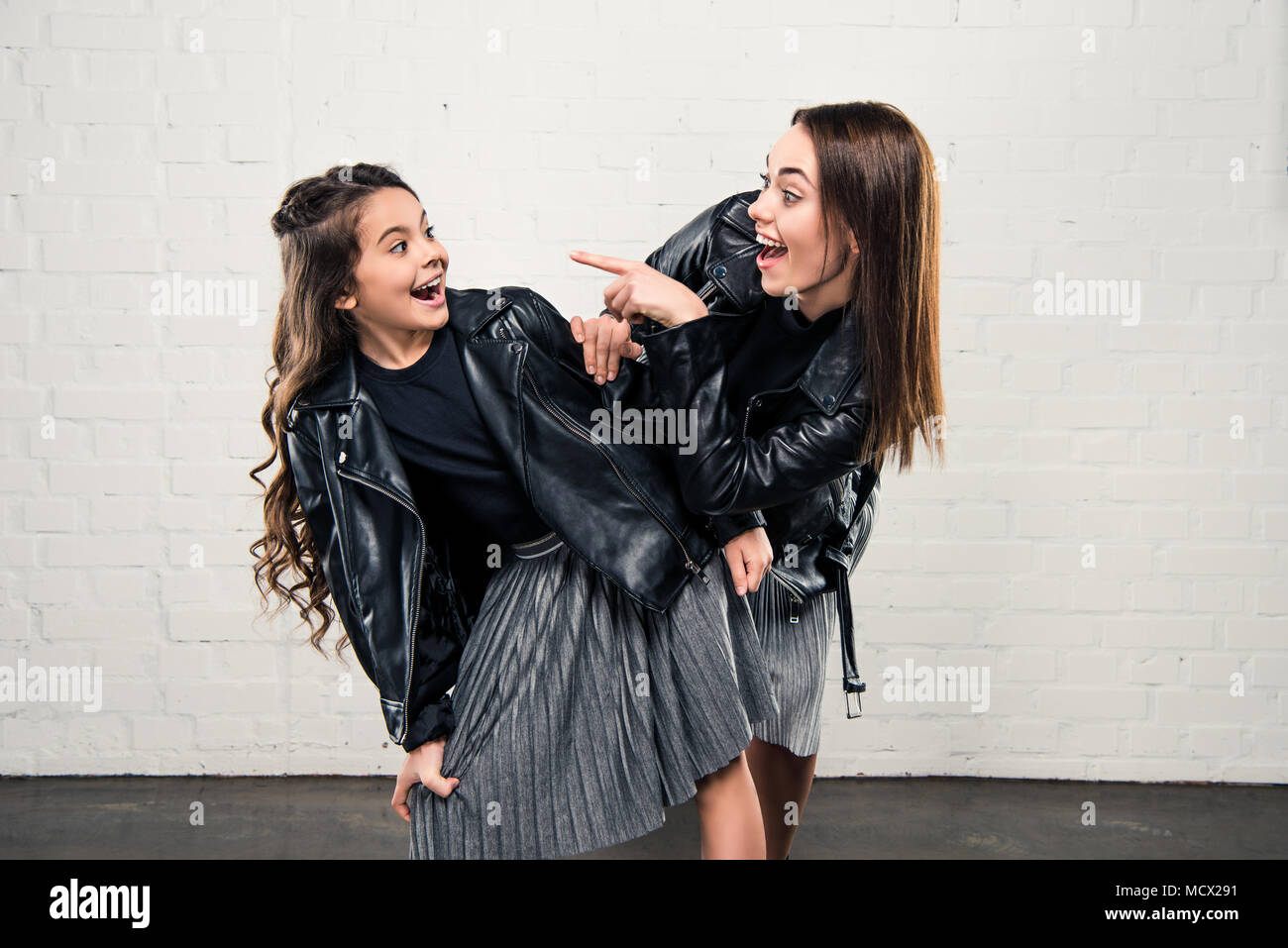 Laughing stylish mother pointing on smiling daughter Stock Photo - Alamy