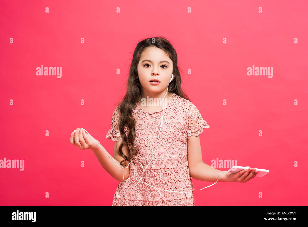 Kid standing with smartphone and earphones isolated on red Stock Photo ...