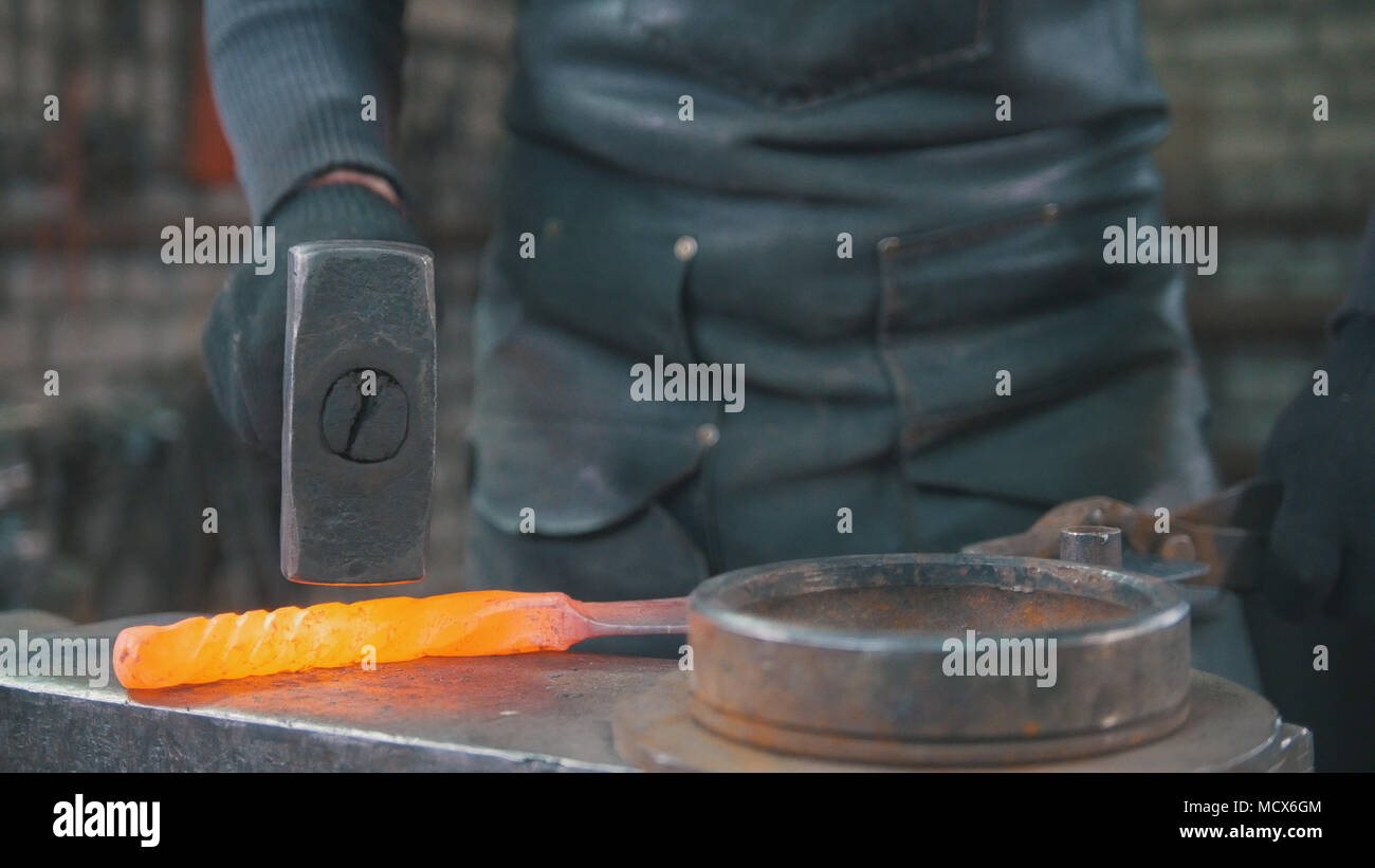 The smith gives shape with a hammer to a red-hot metal object Stock ...
