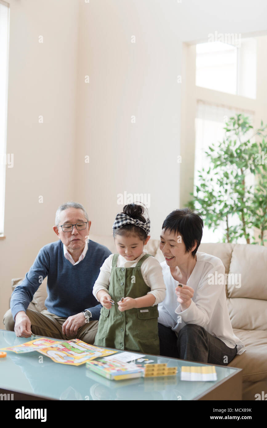 Grandparents and grandchild playing board game Stock Photo - Alamy