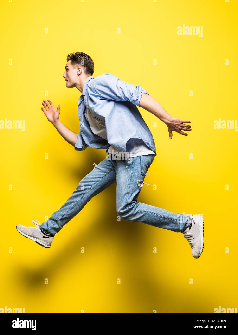 Young handsome man jumping on yellow background Stock Photo - Alamy