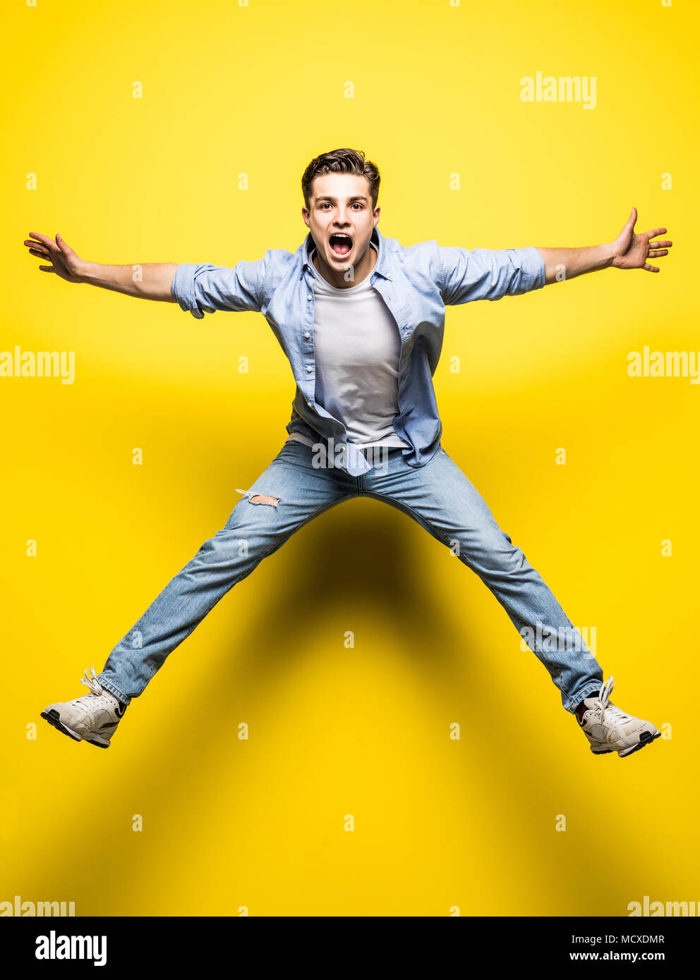 Young handsome man jumping on yellow background Stock Photo - Alamy