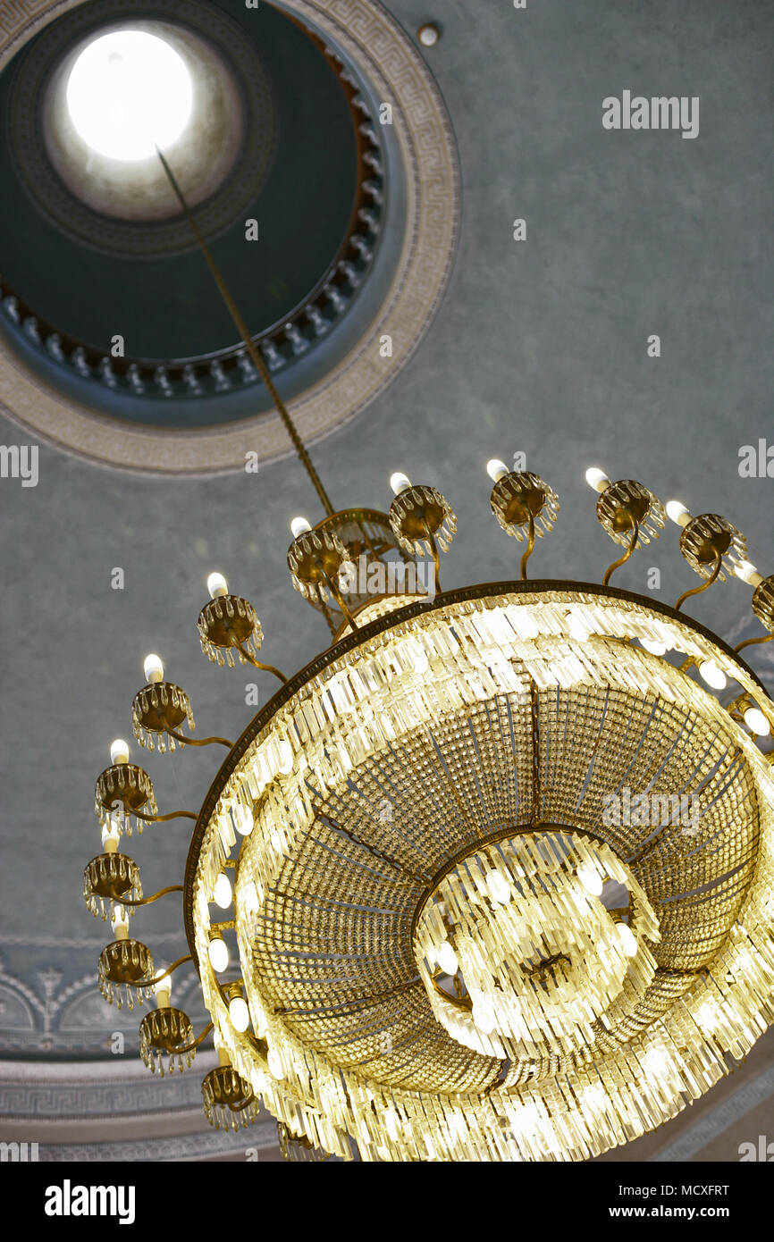 big chandalier with lights hanging down a round hole in the ceiling ...