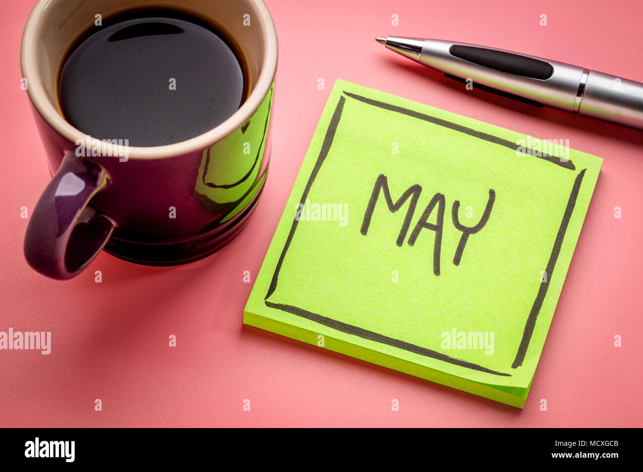 May - handwriting in black ink on a sticky note with a cup of coffee ...